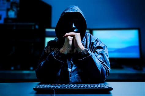 Anonymous Computer Hacker In White Mask And Hoodie Obscured Dark Face Holds A Laptop Tight In