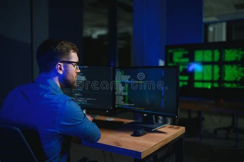 male programmer working on desktop computer at white desk in office