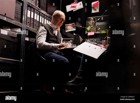 Elderly Investigator Analyzing Missing Person Report Working Late At