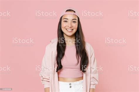 파스텔 핑크 월 배경 스튜디오 초상화에 고립 포즈 캐주얼 옷 모자에 젊은 아시아 여자 소녀 미소 사람들은 진지한 감정 라이프 스타일 개념 복사 공간을 모의합니다 카메라를