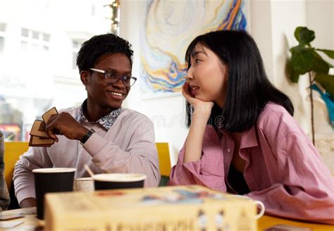 Cute Mixed Race Couple Of Teenagers Enjoying Milkshake At Cafeteria
