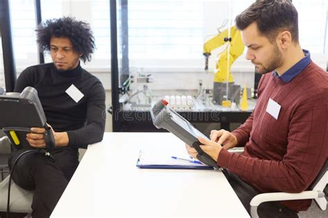 Engineers Programming Robotic Arm In Modern Industrial Setting For
