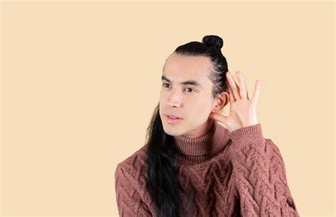 남자는 소문이나 험담을 듣고 귀를 통해 손으로 미소 고립 된 배경에 스웨터에 자신의 귀 개념에 자신의 손으로 듣고 제스처를 만든다 청각 장애의 개념 30 34세에 대한 스톡