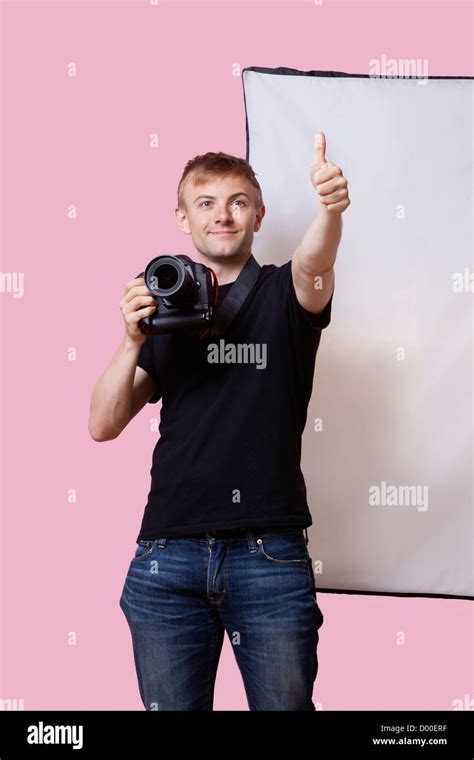 Happy Photographer Holding Camera With Thumbs Up Gesture Over Pink