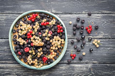 건포도 열매 노란색 빨간색 검정과 빨강 나무 딸기 소박한 도자기 그릇 나무 오래 된 테이블에의 다양 한 위에서 보기 0명에 대한