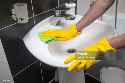 마이크로 화이버 천과 세제를 사용하여 싱크대와 수도꼭지를 청소하는 보호 장갑의 손 가사 및 위생의 개념 30 34세에 대한 스톡