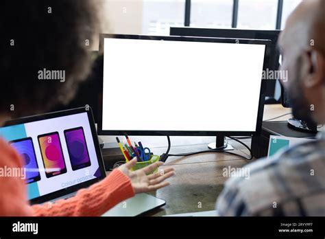 Rear View Of Diverse Male And Female Designers Discussing At Computer With Copy Space In Office