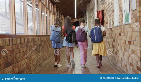 Rear View Of Happy Diverse Schoolgirls With School Bags Walking In