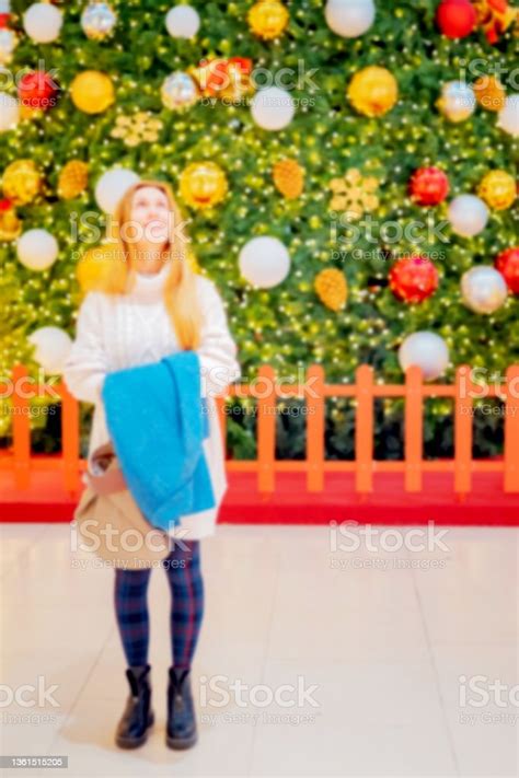 큰 우아한 크리스마스 트리 옆에 서있는 동안 위를 올려다 보는 미소 여자 축제 분위기 복사 공간이 있는 이미지입니다 흐릿한 그림 12월에 대한 스톡 사진 및 기타 이미지