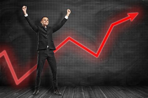 검은 색 그래프 가루 벽 근처 그의 뒤에 올라가는 빨간색 그래프 화살표와 승리 제스처에 팔을 올리는 행복 한 사업가의 전면 전체