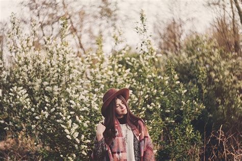 저녁 햇빛에 공원에 서 있는 아름 다운 머리와 모자에 판 쵸 Hipster 세련 된 소녀 봄 정원에서 편안한 세련 된 옷에 여성