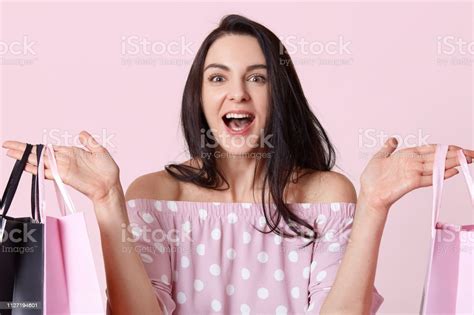 얼굴만 기쁘게 어두운 머리 젊은 여자의 쇼핑 가방을 보유 하 고 즐겁게 좋은 기 뻐 날 성공적인 구매 라이트 핑크 배경 위에 모델은 사람과 구매 개념 가방에 대한 스톡 사진