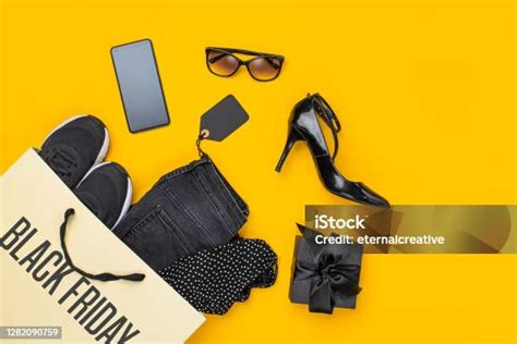 노란색 배경에 옷이 쏟아지는 종이 쇼핑백 블랙 프라이데이 컨셉 쇼핑백에 대한 스톡 사진 및 기타 이미지 쇼핑백 플랫 레이 소매 소비자주의 Istock