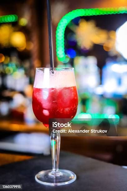 키가 큰 유리에는 높은 흰색 거품이 있는 불투명한 블러드 레드 칵테일과 검은 빨대를 가지고 있습니다 보케의 밝은 조명의 배경에 대한 바 메뉴의 촬영 0명에 대한 스톡 사진