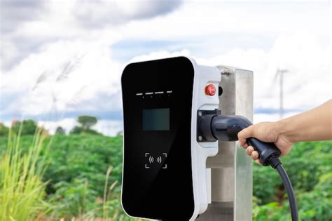 점진적인 자연 경관 및 풍력 터빈이 있는 Ev에 핸드 인서트 커넥터 플러그 프리미엄 사진