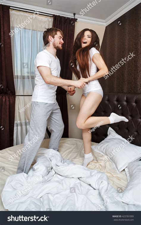 Happy Married Couple Jumping On The Bed In His Own Bedroom Marital