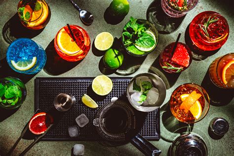 녹슨 녹색 바 카운터에 칵테일이 놓여 있습니다 믹솔로지 개념입니다 여름 칵테일 파티를 위한 다채로운 독알코올 음료와 저알코올 음료 모음 어두운 배경 바 도구 하드 라이트 0