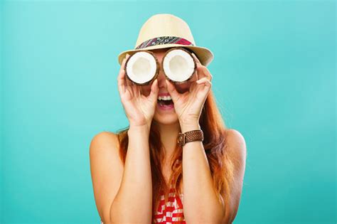 수영복과 밀짚 모자를 쓰고 있는 여성이 눈 근처에 코코넛 의 두 부분을 들고 있습니다 거리에 대한 스톡 사진 및 기타 이미지 거리 과일 노랑 Istock