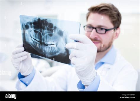 MODEL RELEASED Dentist Looking At X Ray Image With Dental Assistance In Background Stock Photo