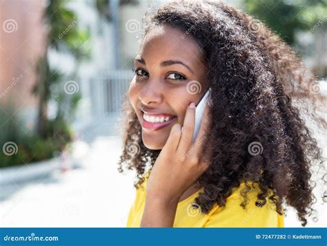 Усмехаясь латинская женщина с вьющиеся волосы на телефоне в лете Стоковое Фото изображение