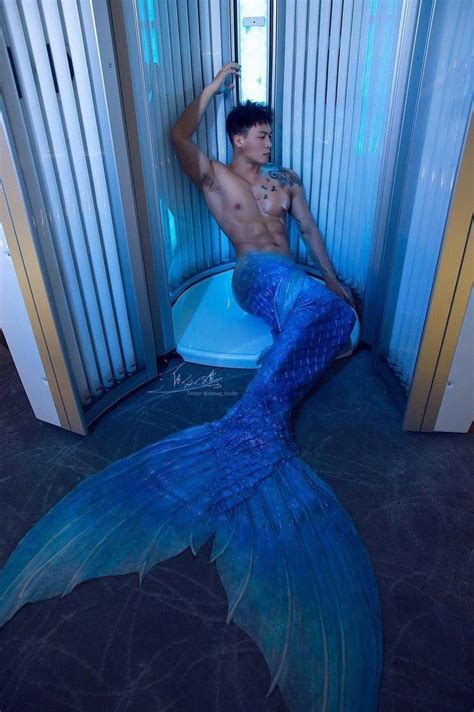 A Man Sitting On Top Of A Toilet Next To A Blue Mermaid Tail