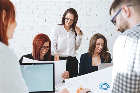 테이블 주위에 앉아있는 젊은 동료의 그룹 및 현대 노트북 종이 문서 다이어그램 및 그래프 Coworking 로프트 스튜디오에서 작업 Teamworking 개념입니다 가정의